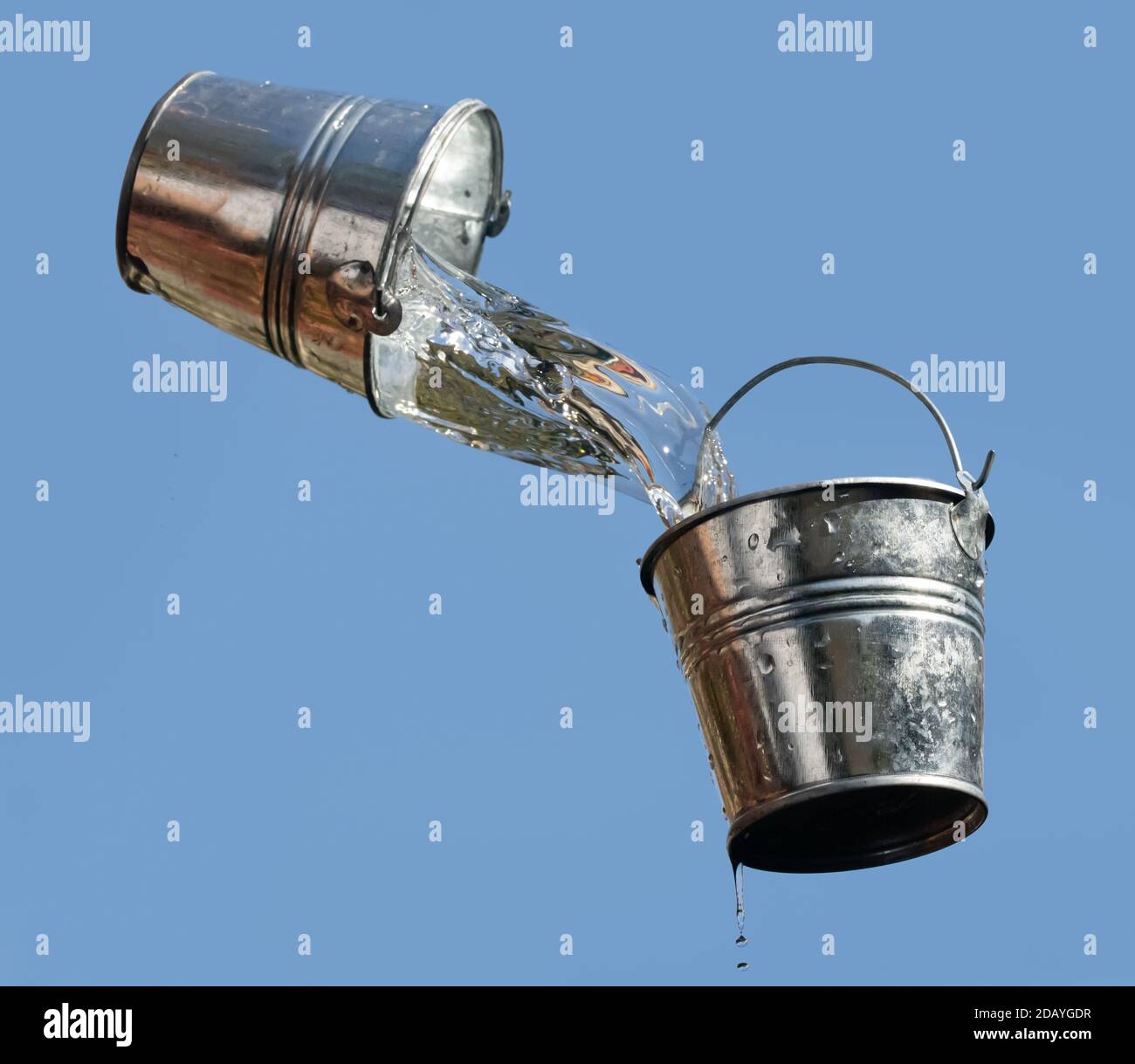 A pouring water from bucket to bucket, on a background of blue sky ...