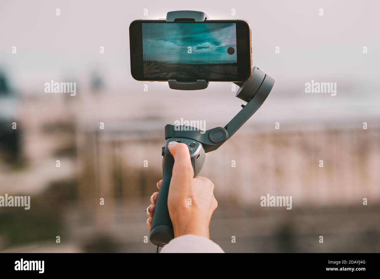 Woman hand with a gimbal for smartphone. Taking a photo of the sky ...
