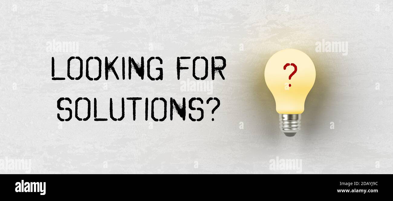 bright lightbulb on paper background with message LOOKING FOR SOLUTIONS ...