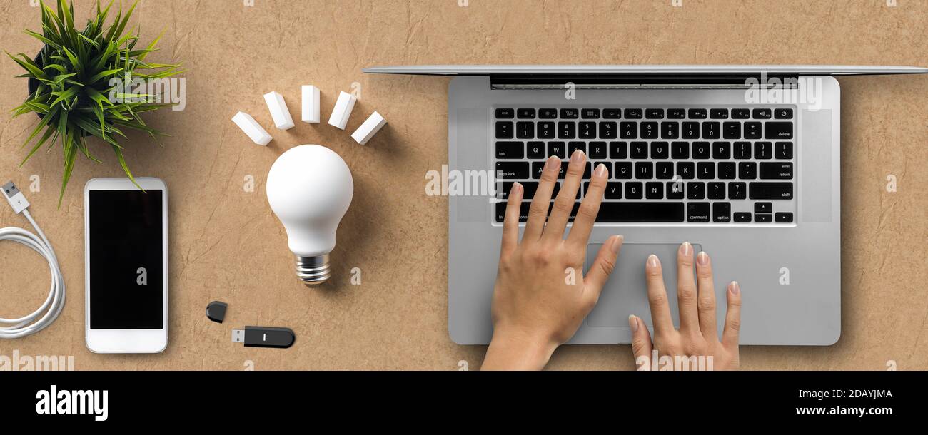 hand over a computer with office equipment and a white lightbulb on ...