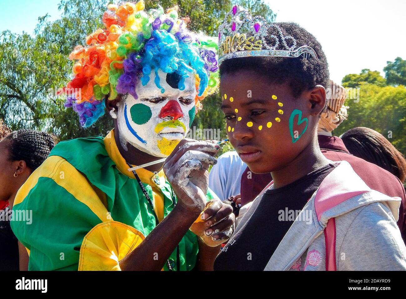 Kudzai Chomo, a clown, paints the face of Patience Nkomo at the annual ...