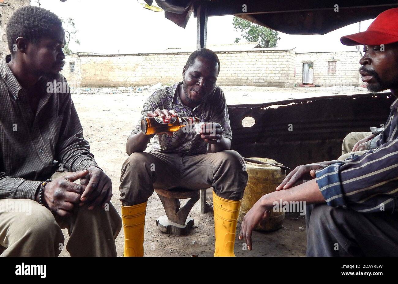 Misheck Mwale (center), pours Kachasu beer with friends in Chibolya, a ...
