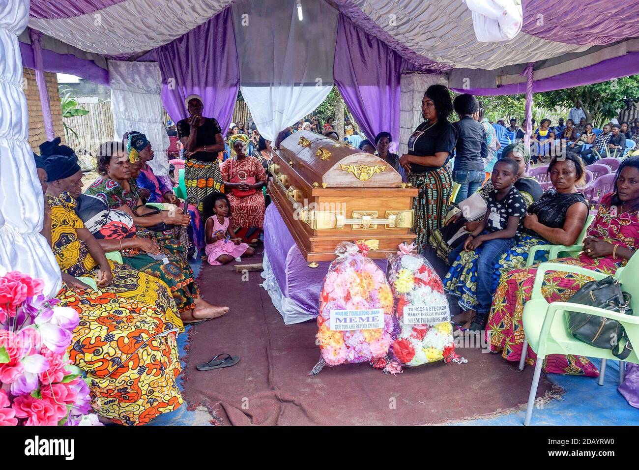 Funeralgoers gather under a purple canopy at a funeral in Kisangani ...