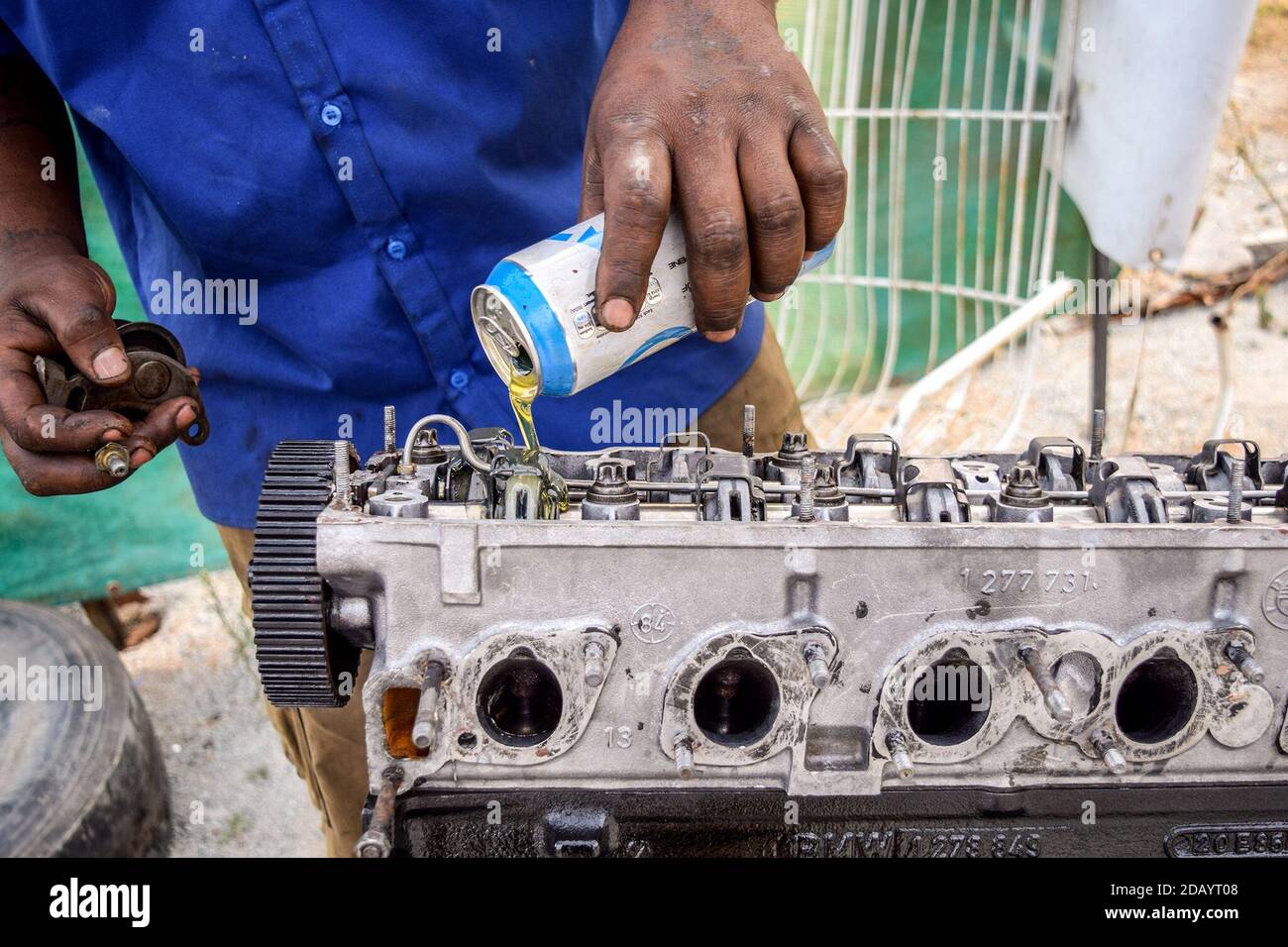 Kuziva Nkomo, a mechanic and spinner, pours oil into an engine being ...