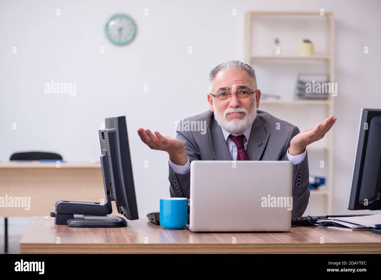 Old boss sitting at desktop in the office Stock Photo - Alamy