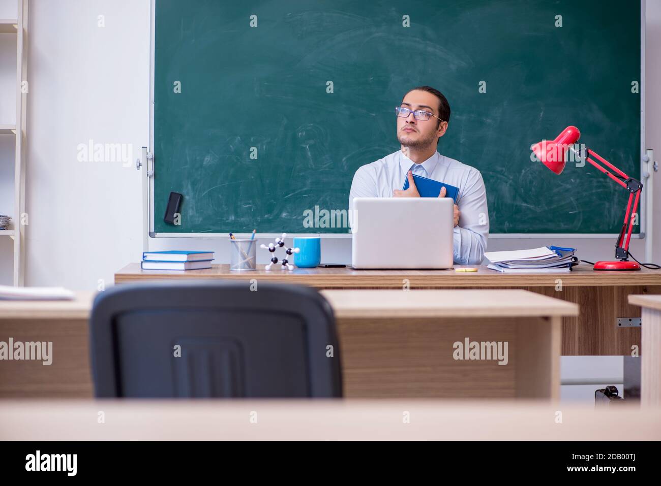 Young teacher in front of green board Stock Photo - Alamy