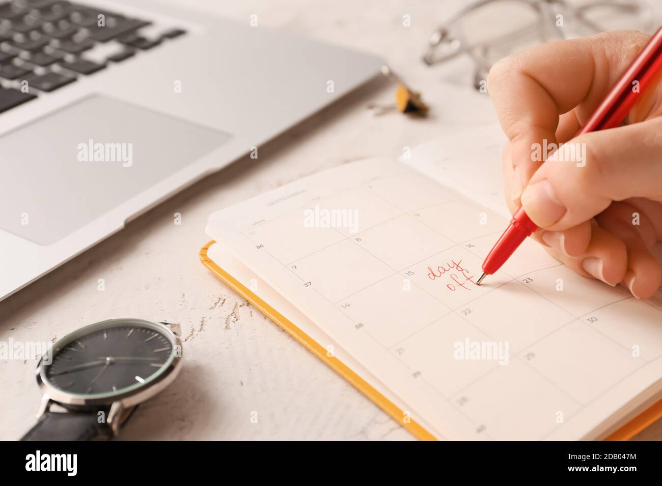 Woman marking day off in calendar at workplace Stock Photo - Alamy