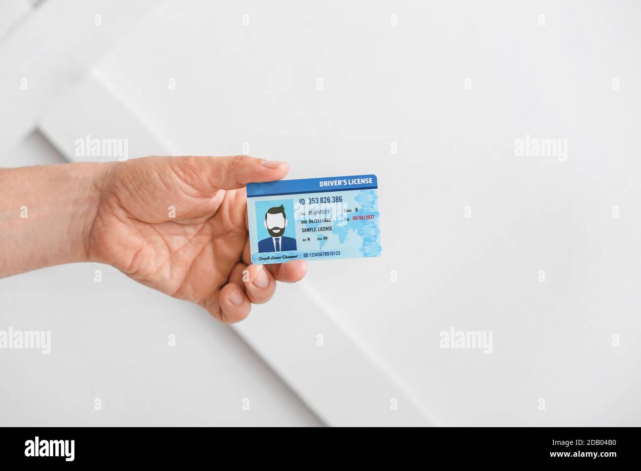 Male hand with driving license on light background Stock Photo - Alamy