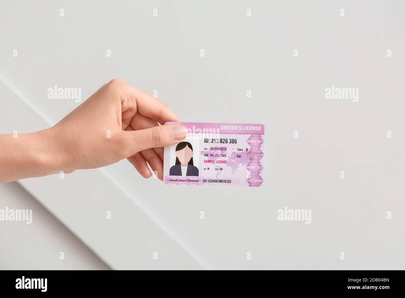 Female hand with driving license on light background Stock Photo - Alamy