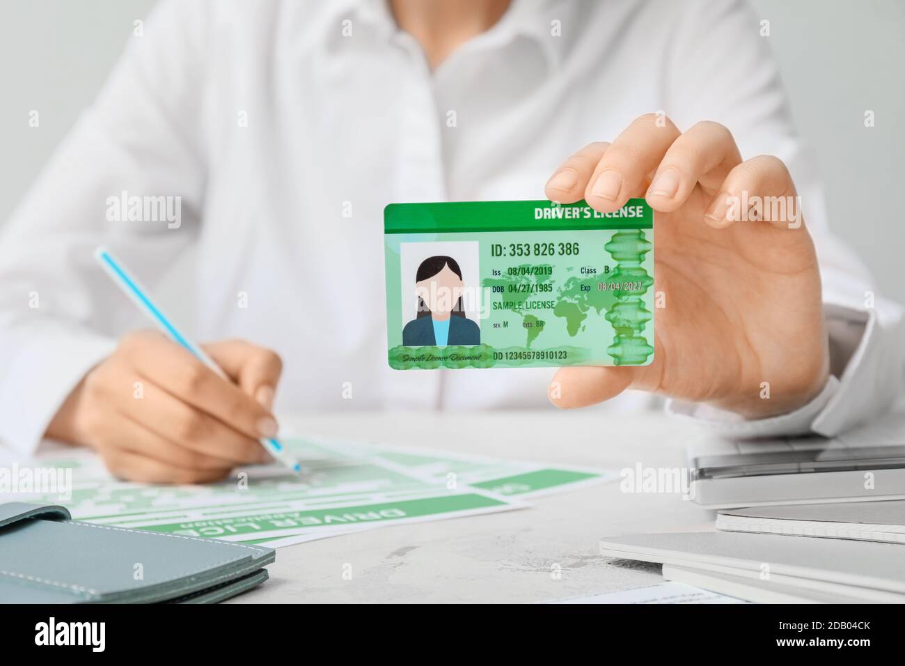 Woman with driving license and application form at table Stock Photo ...