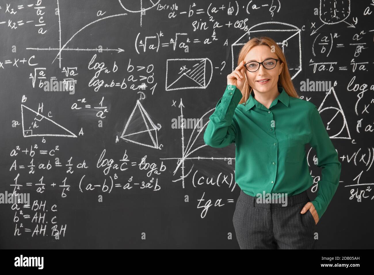 Mature maths teacher near blackboard in classroom Stock Photo - Alamy