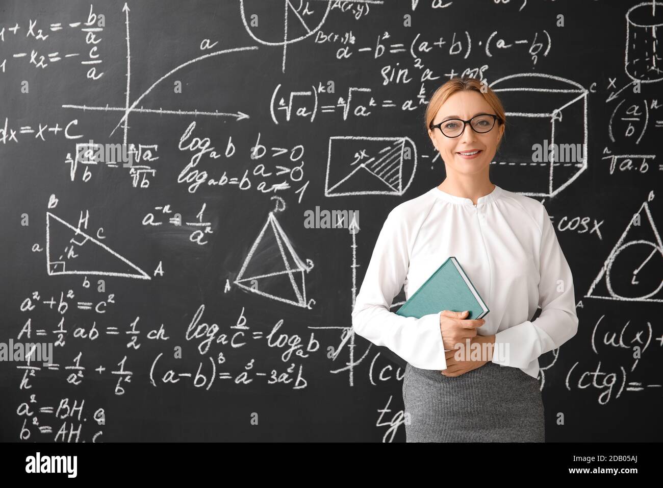 Mature maths teacher near blackboard in classroom Stock Photo - Alamy