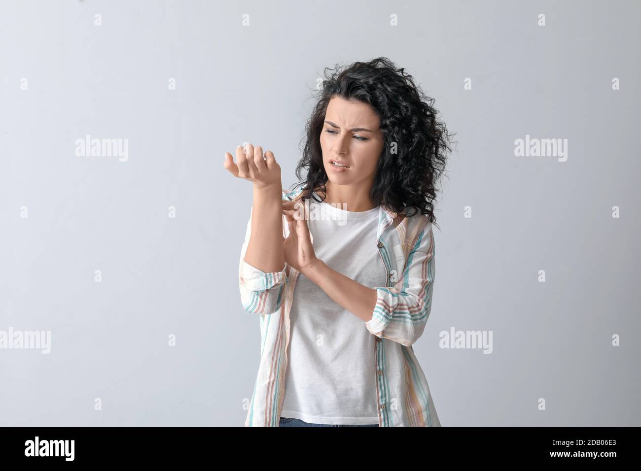 Allergic young woman scratching herself on grey background Stock Photo ...