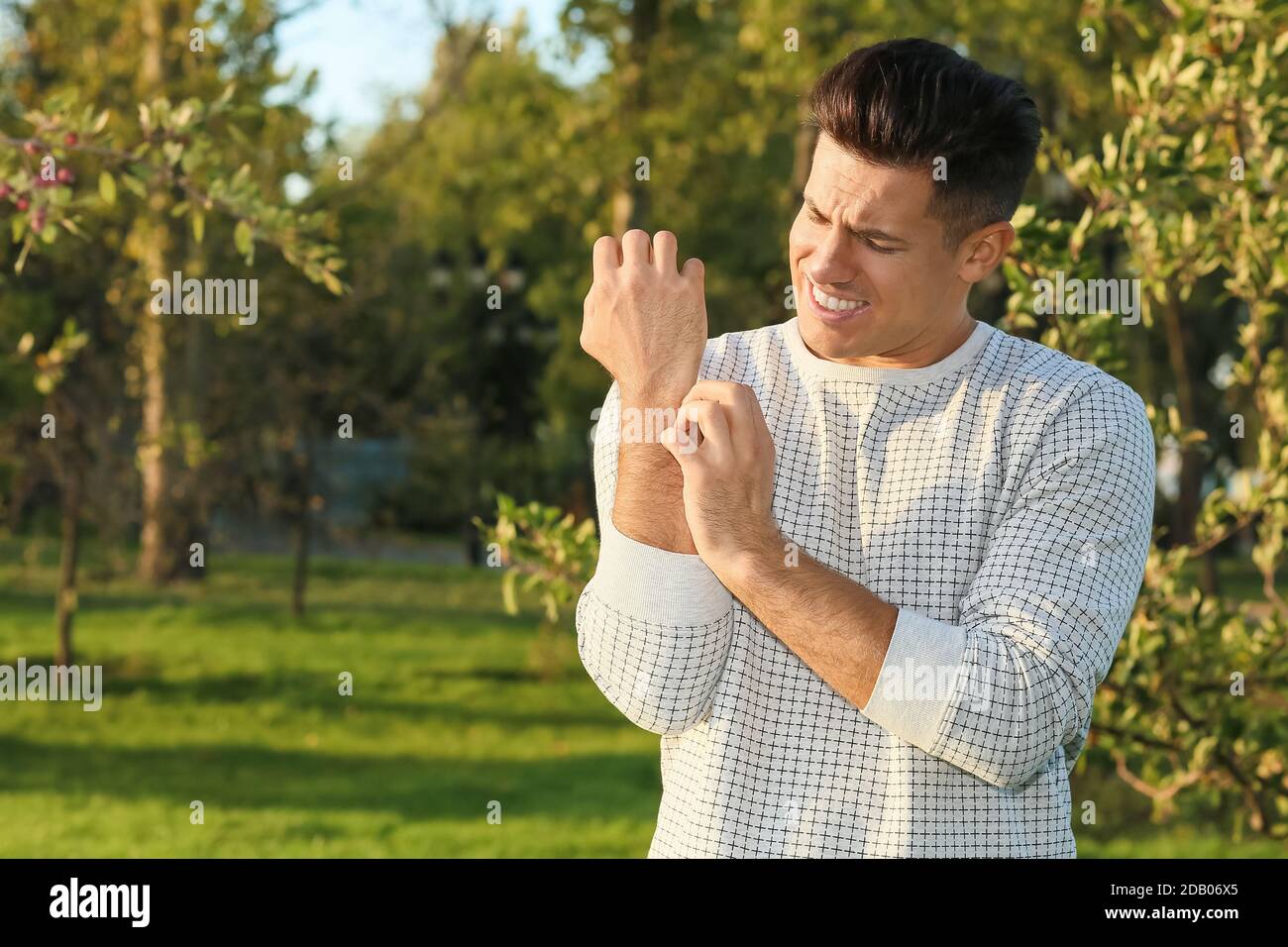 Allergic young man scratching himself outdoors Stock Photo - Alamy