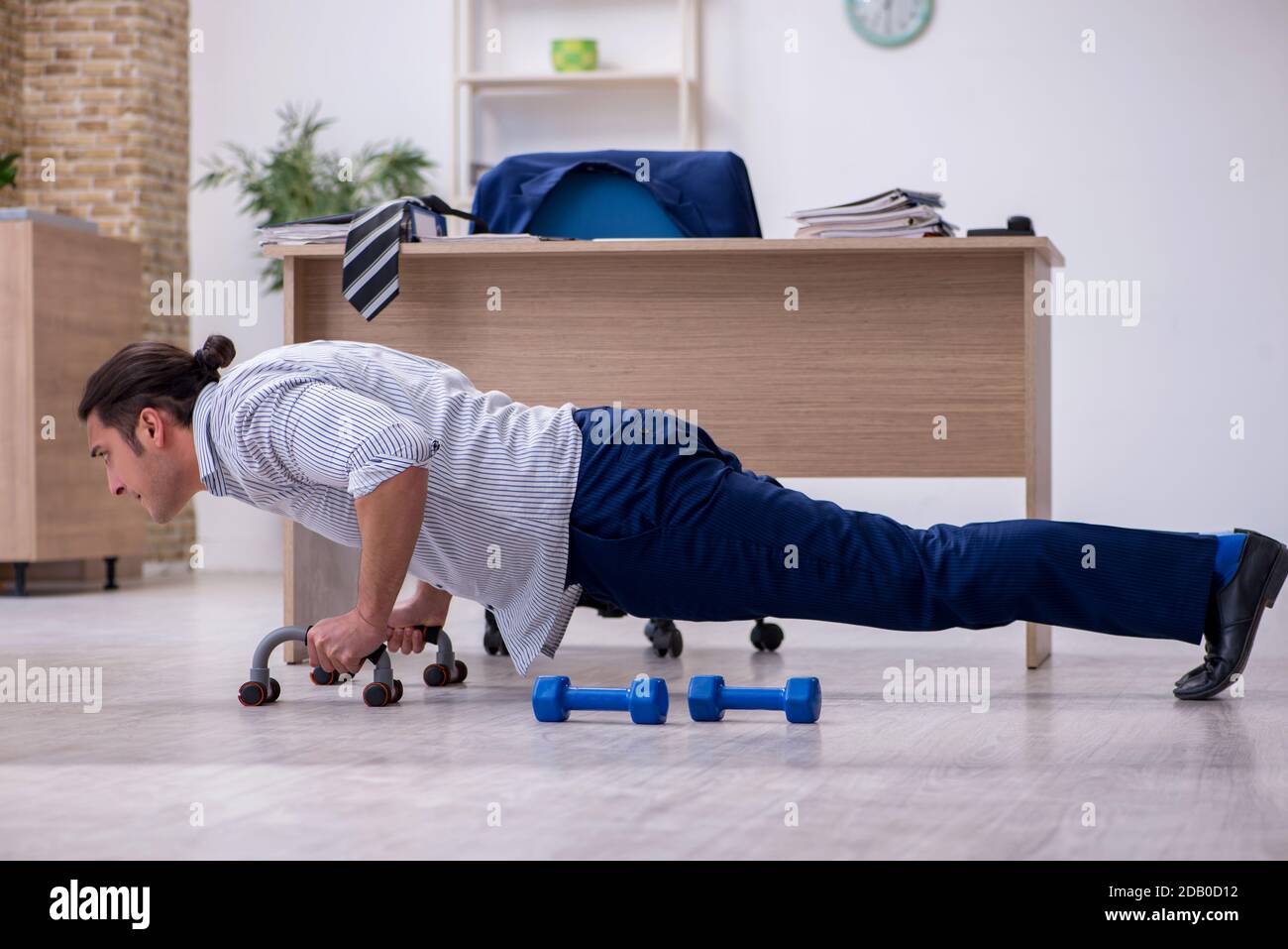 Handsome male employee doing exercises in the office Stock Photo - Alamy
