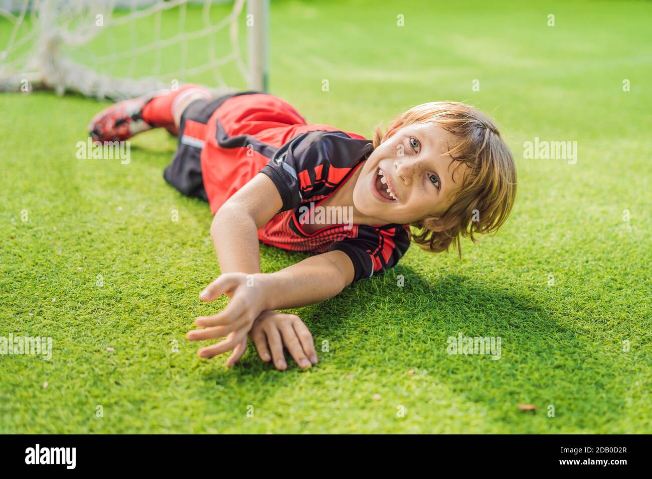 Little cute kid boy in red football uniform playing soccer, football on ...