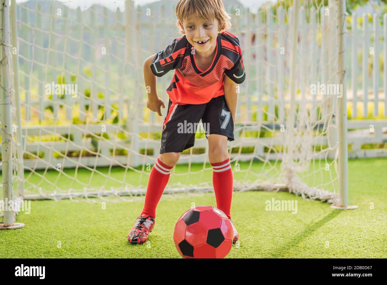 Little cute kid boy in red football uniform playing soccer, football on ...