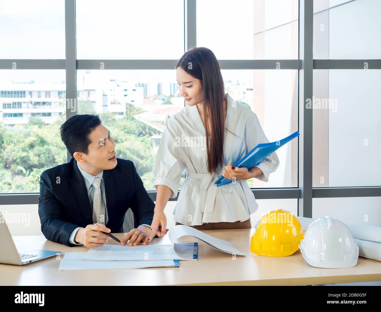 Asian male chief architect or engineer in suit and young female ...