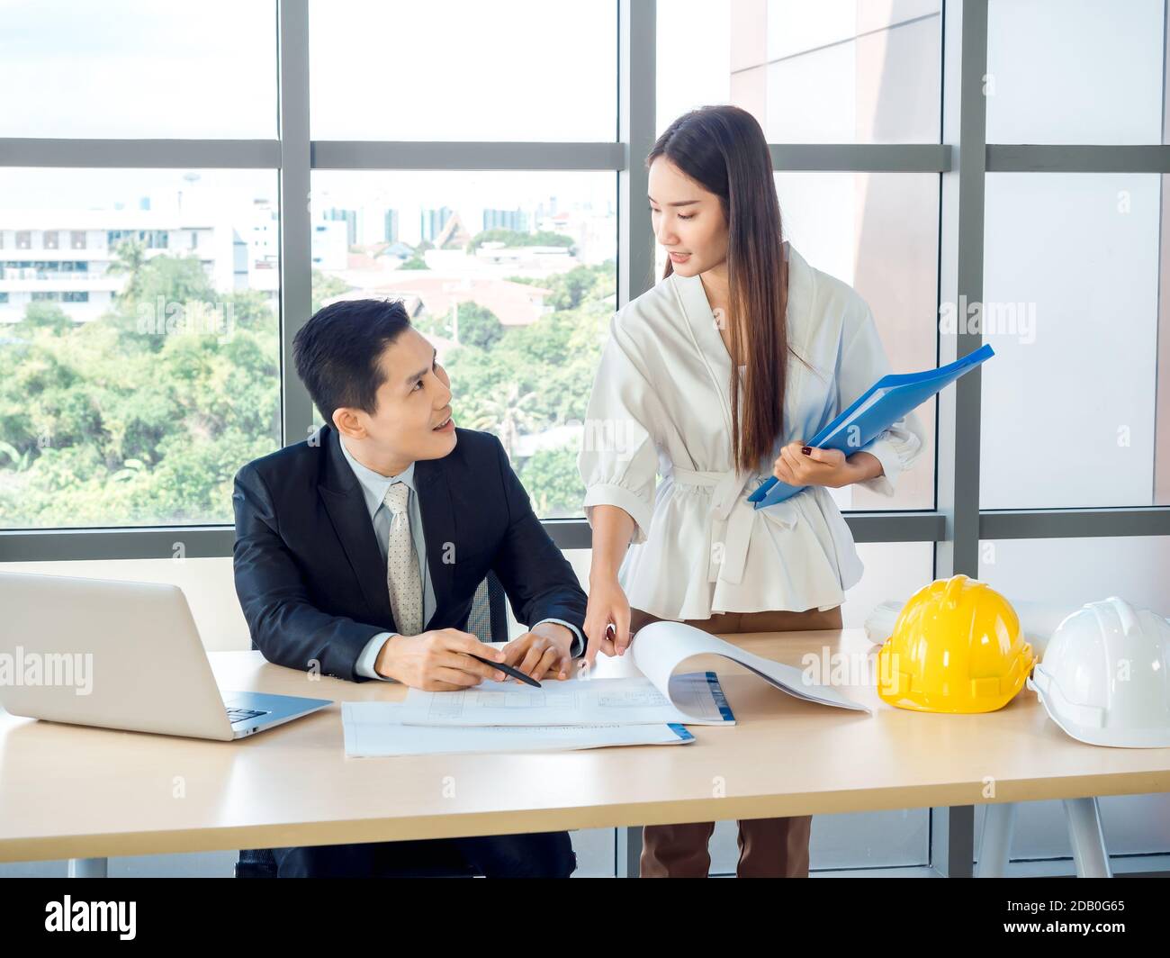 Asian male chief architect or engineer in suit and young female ...