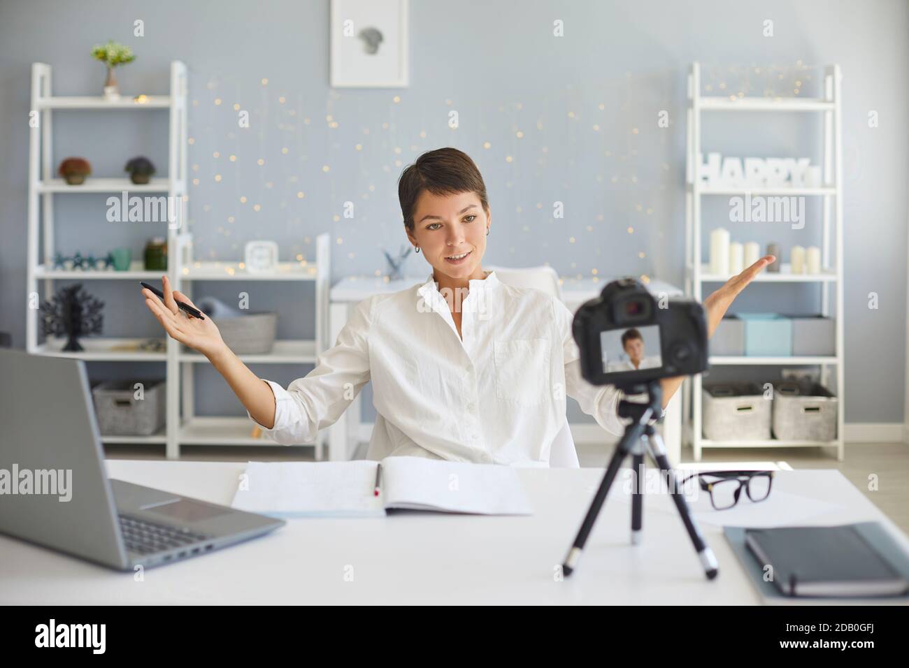 Confident female vlogger recording video on camera sitting at her desk ...