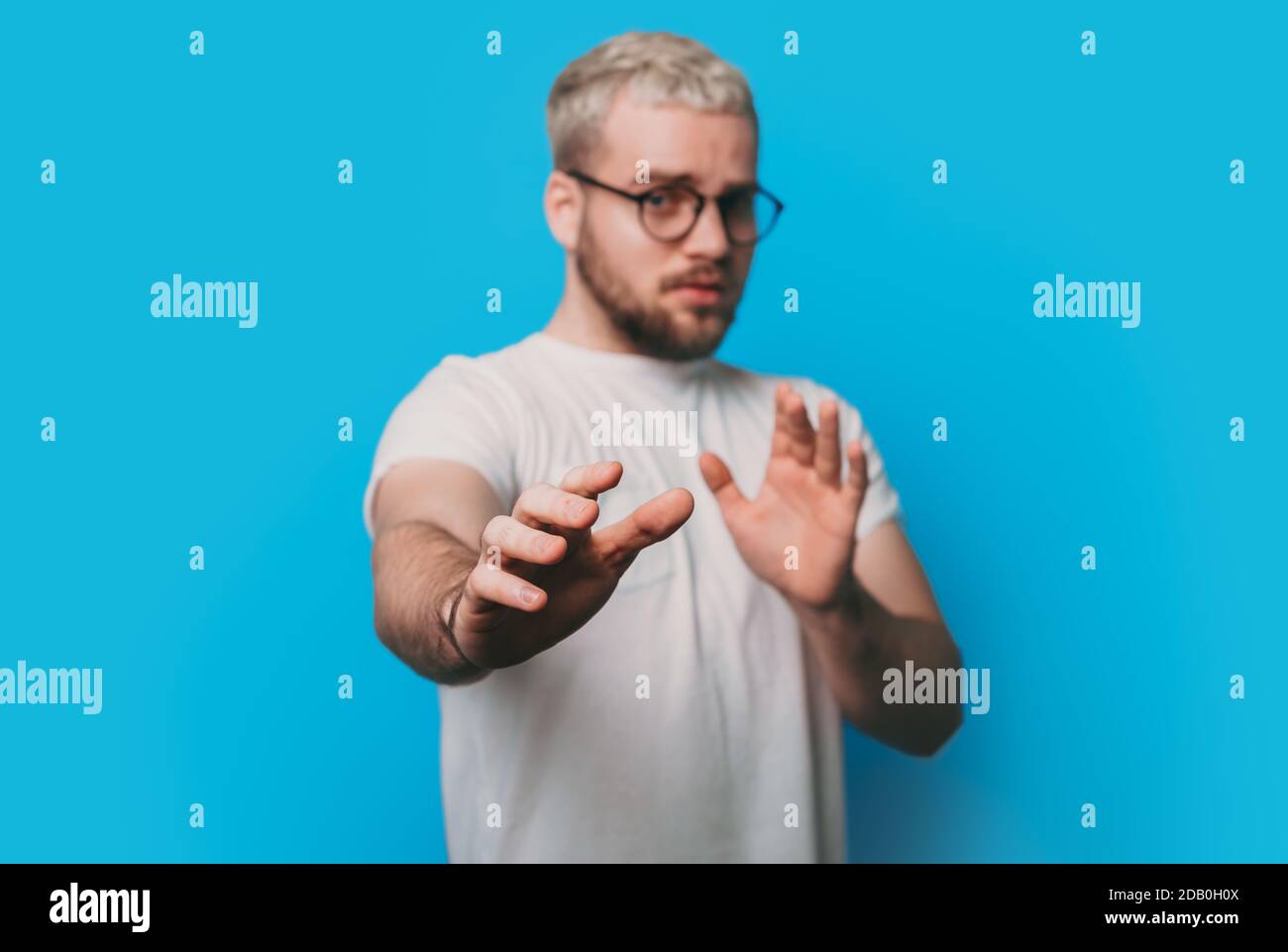Scared man with blonde hair and beard is gesturing the fear sign with ...