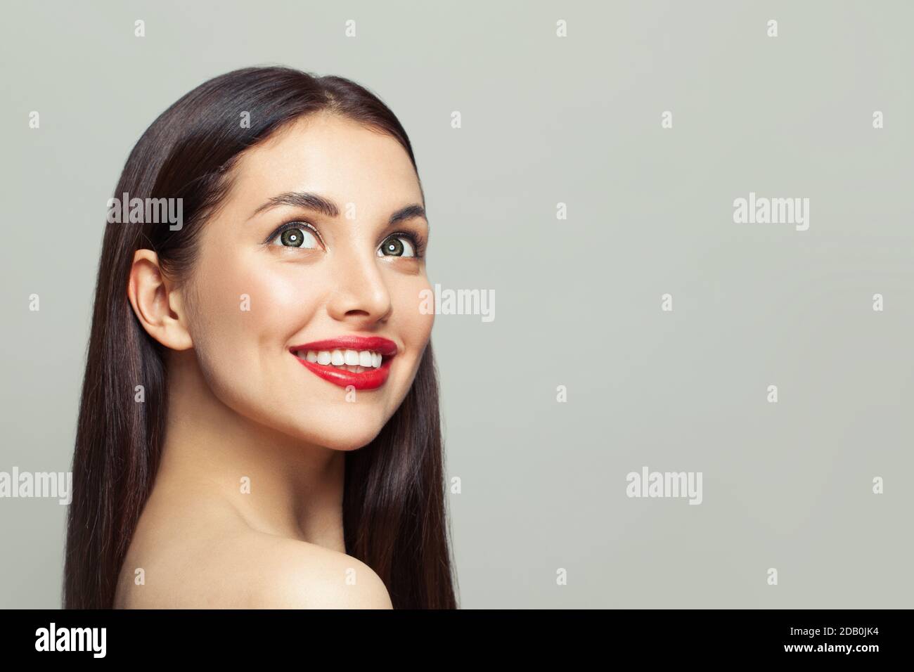 Beautiful woman looking up and smiling on white background, female face ...