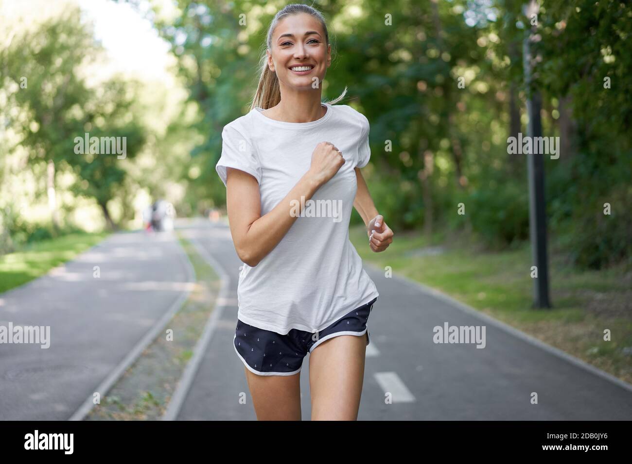 Woman running asphalt road summer park Active sporty caucasian female ...