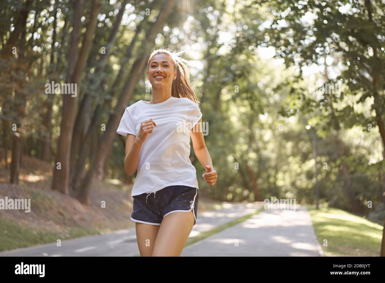 Woman running asphalt road summer park Active sporty caucasian female ...