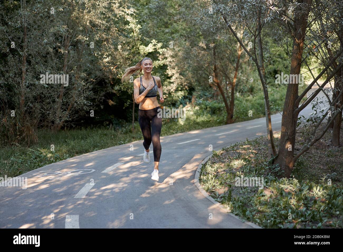 Woman running asphalt road summer park Active sporty caucasian female ...