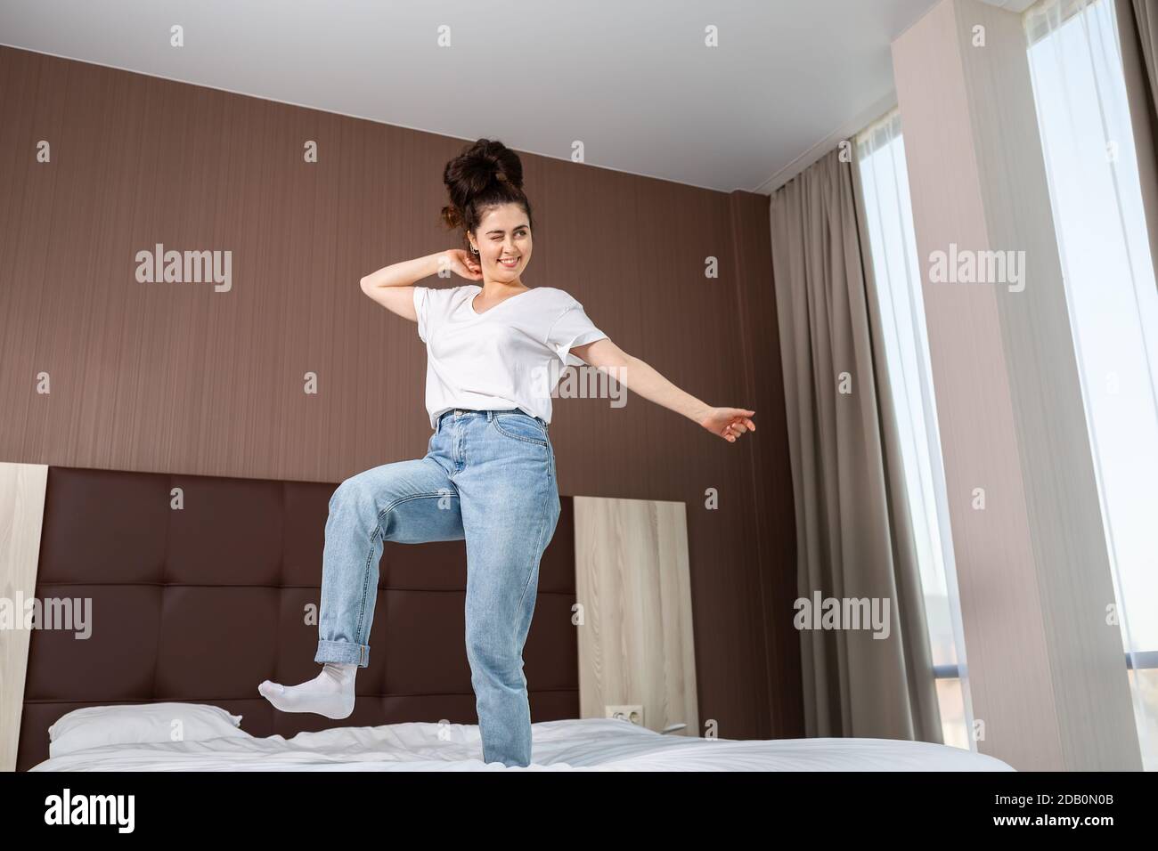 Positive expressions. Happy young woman dancing on the bed in the ...