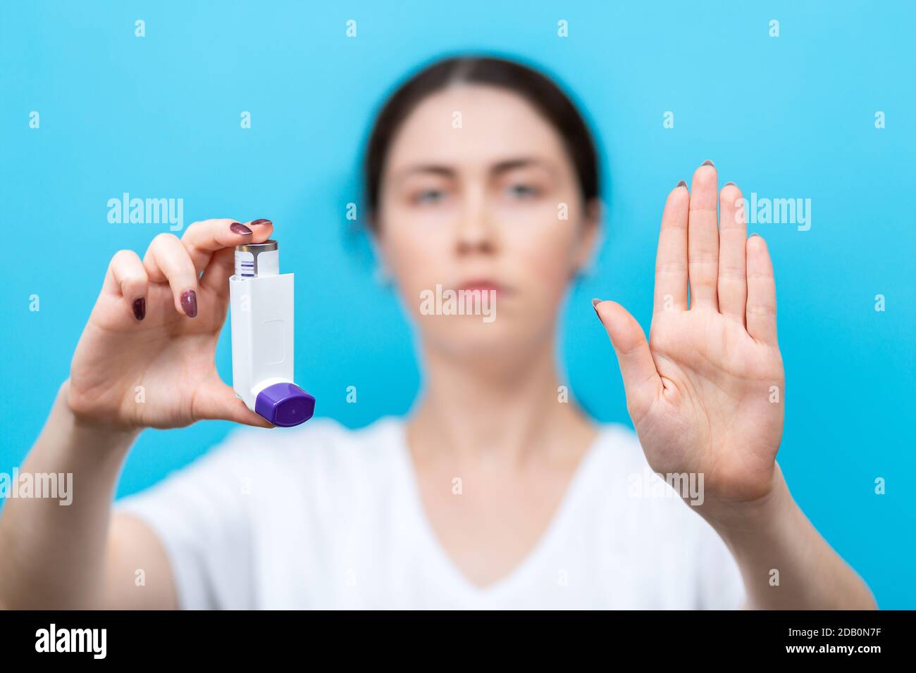 A woman holds an inhaler with medicine in her hand and makes a stop ...