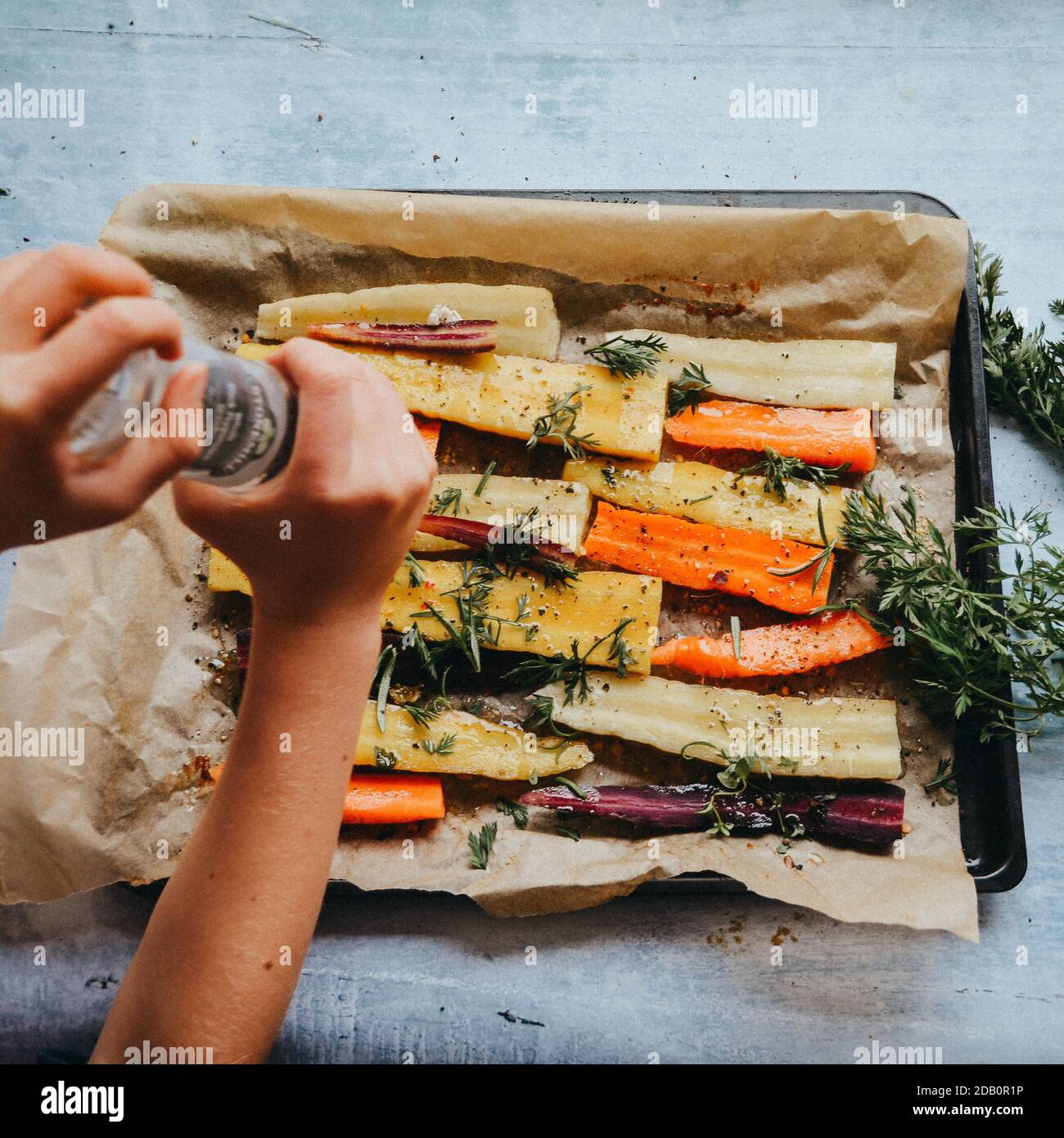Woman adding spices on fresh vegetables in a frying pan Stock Photo - Alamy