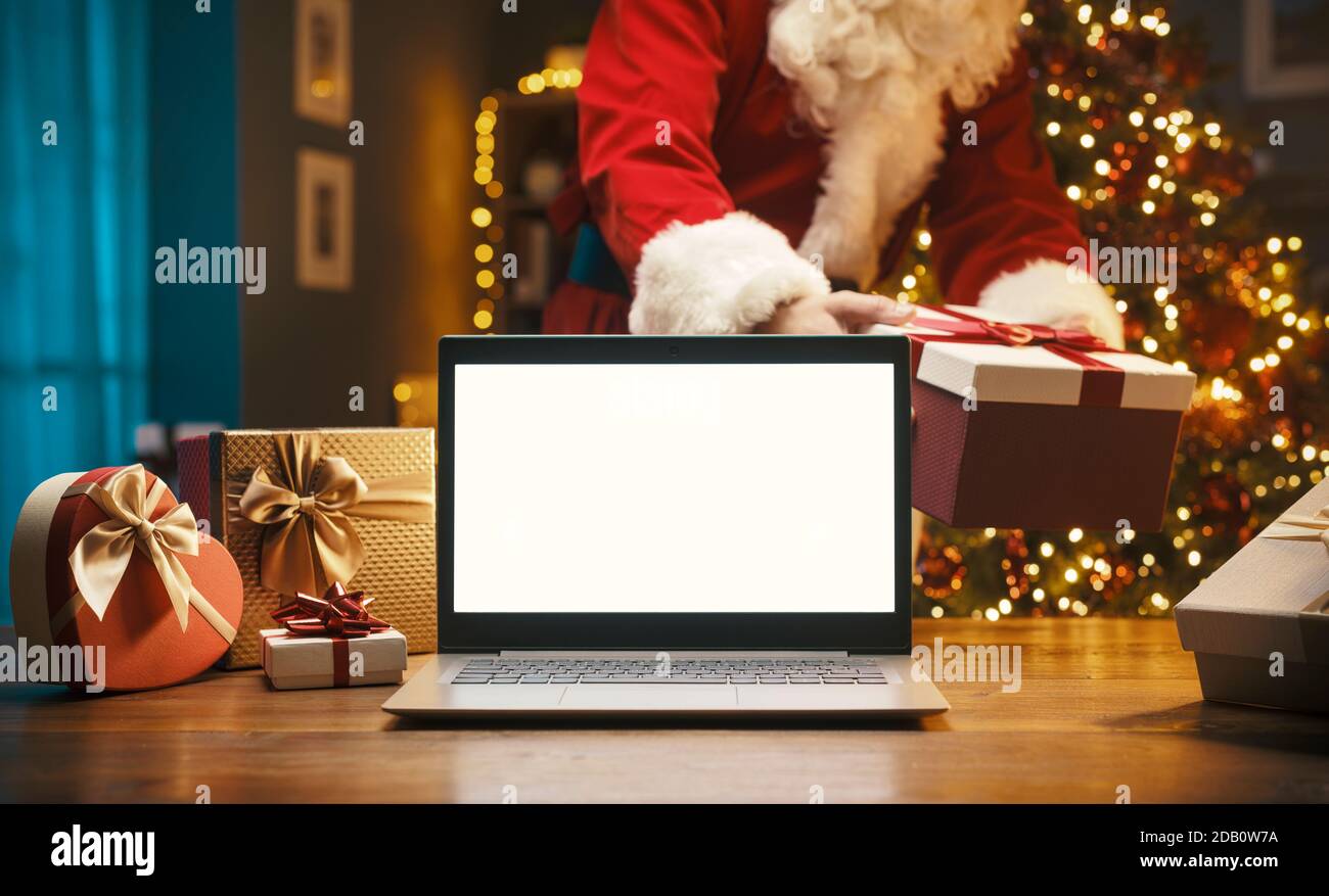 Santa Claus bringing a gift at home on Christmas eve and blank laptop ...