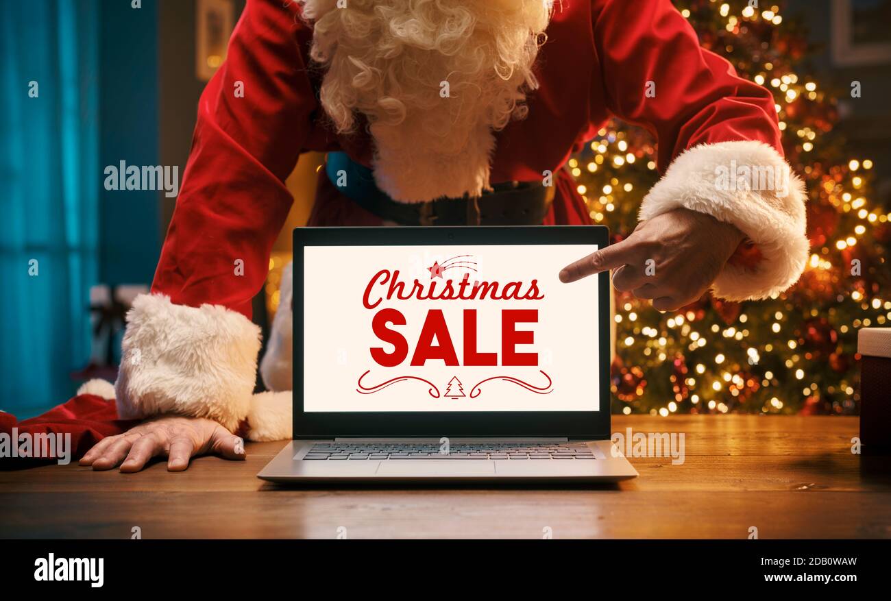 Santa Claus showing Christmas advertisements on the laptop, he is ...