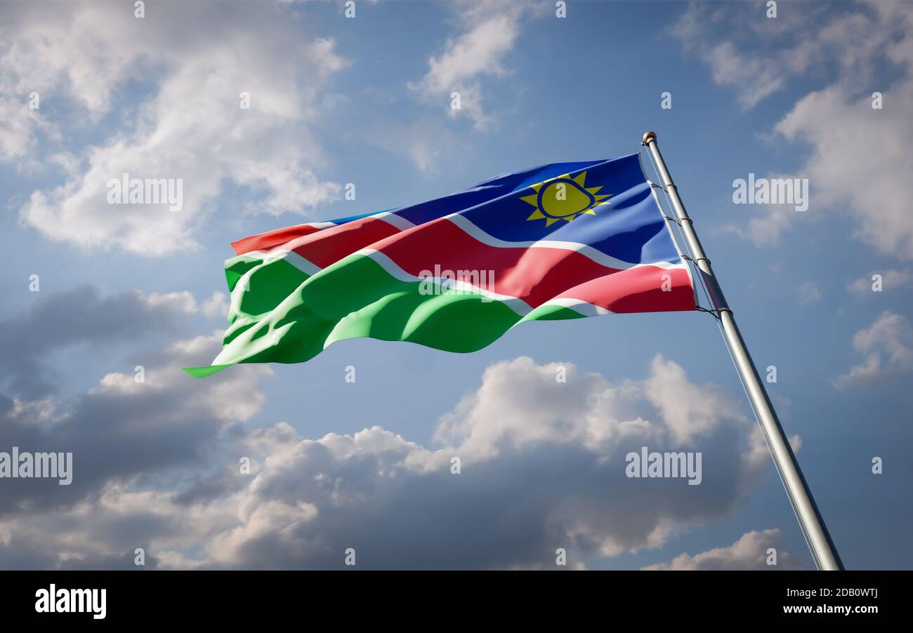 Beautiful national state flag of Namibia fluttering at sky background ...