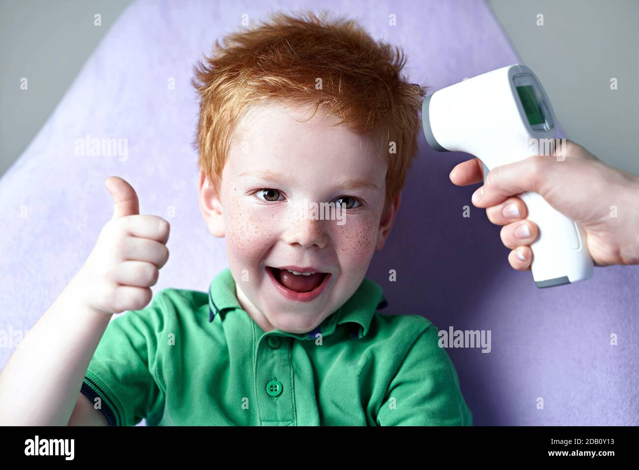 Doctor measures temperature of a cute red haired freckled little boy ...