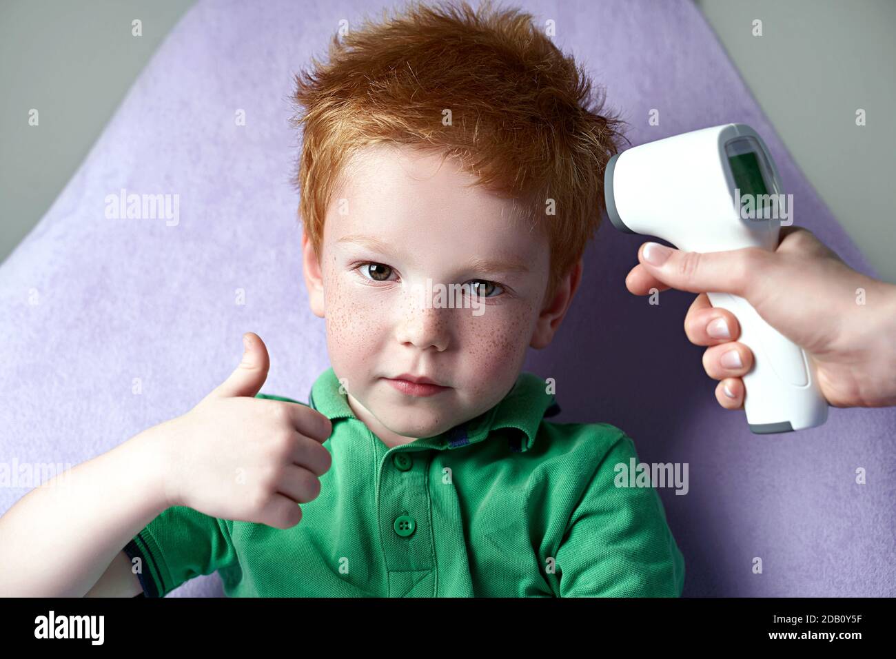 Doctor measures temperature of a cute red haired freckled little boy ...