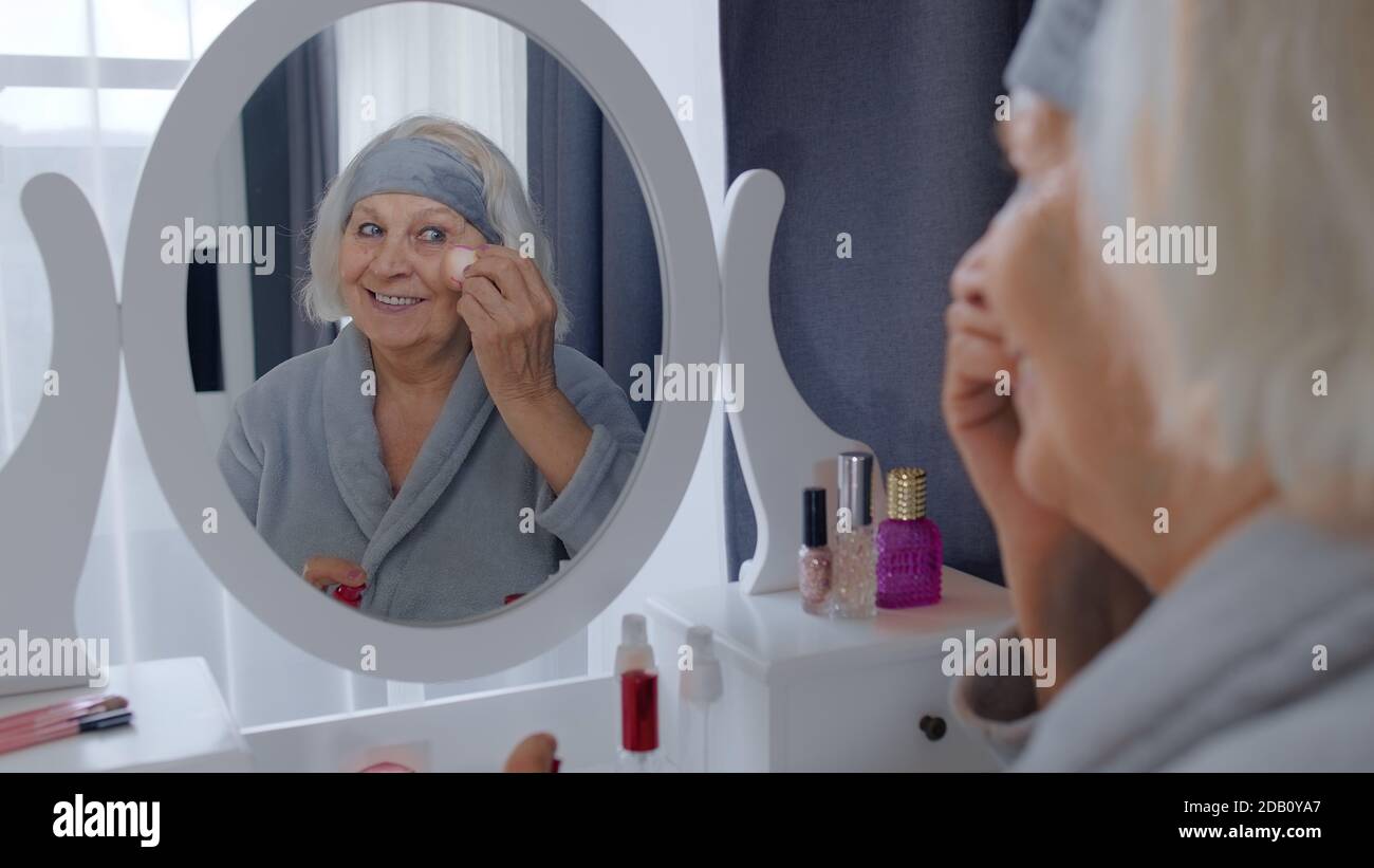 Old senior woman grandmother taking care of skin, applying anti-wrinkle ...