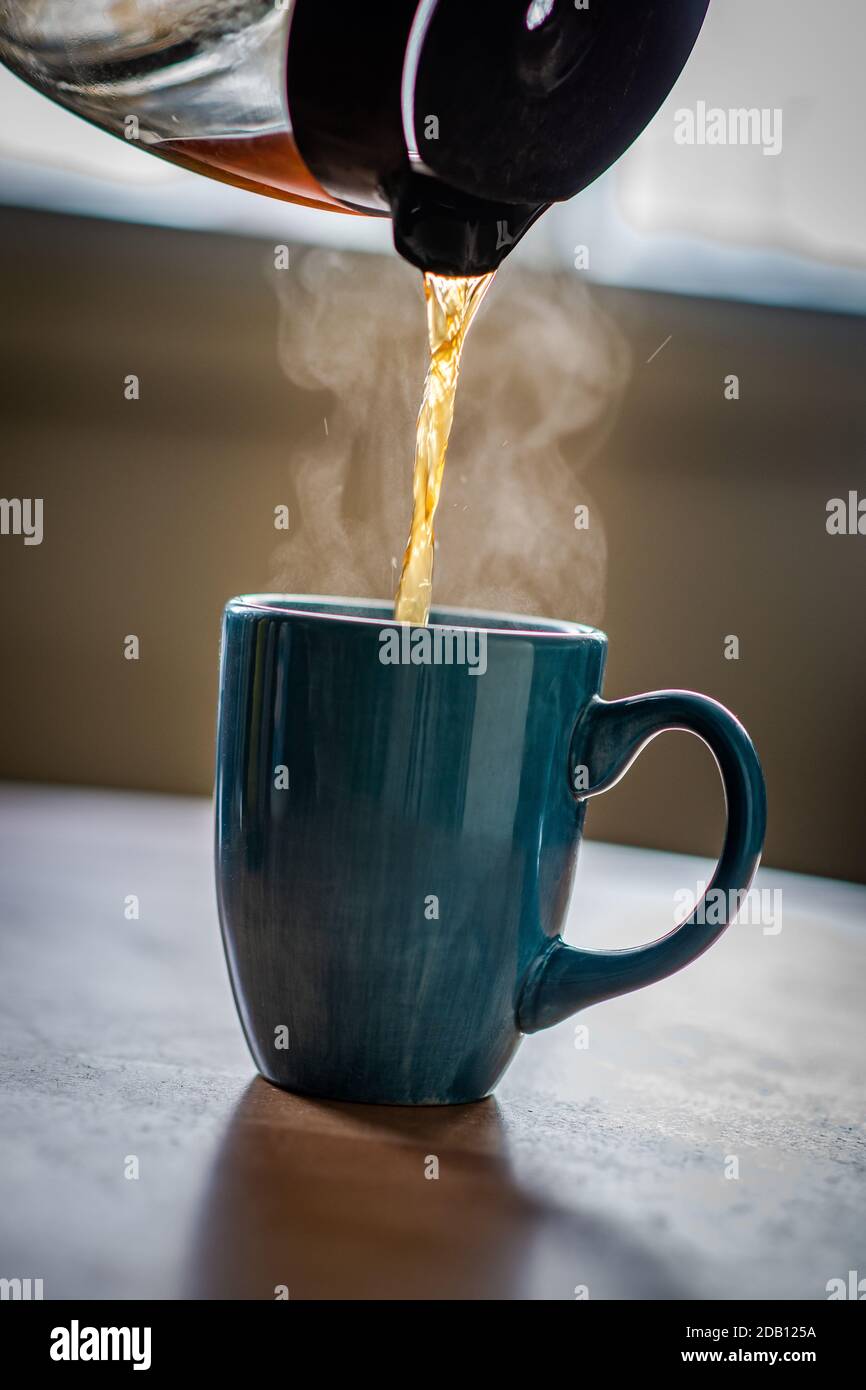 A man pouring tea into a mug from a teapot Stock Photo - Alamy