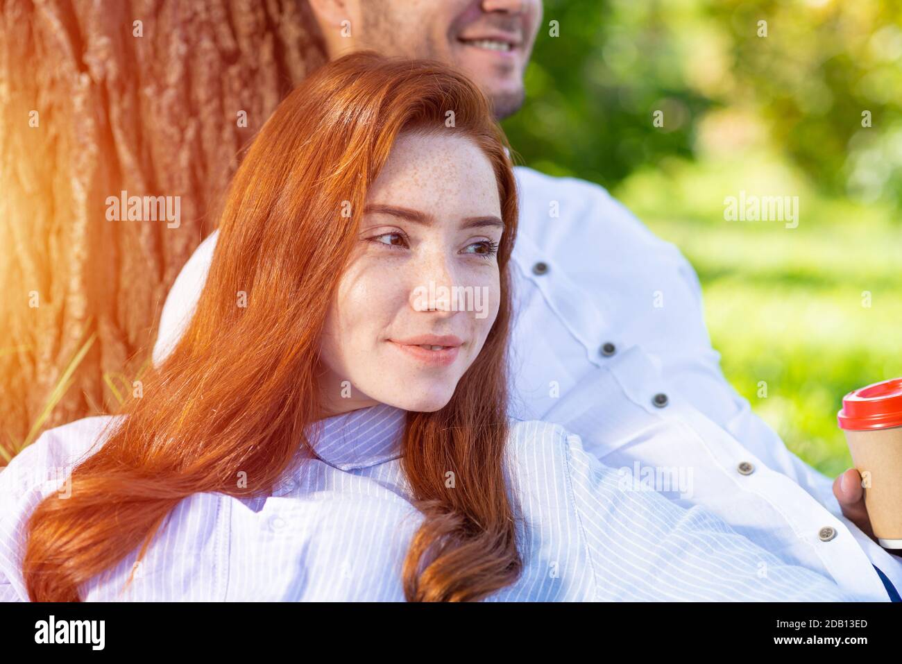 Young couple relaxing with coffee under tree Stock Photo - Alamy