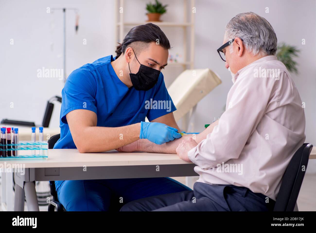 Old patient visiting young male doctor in blood transfusion concept ...