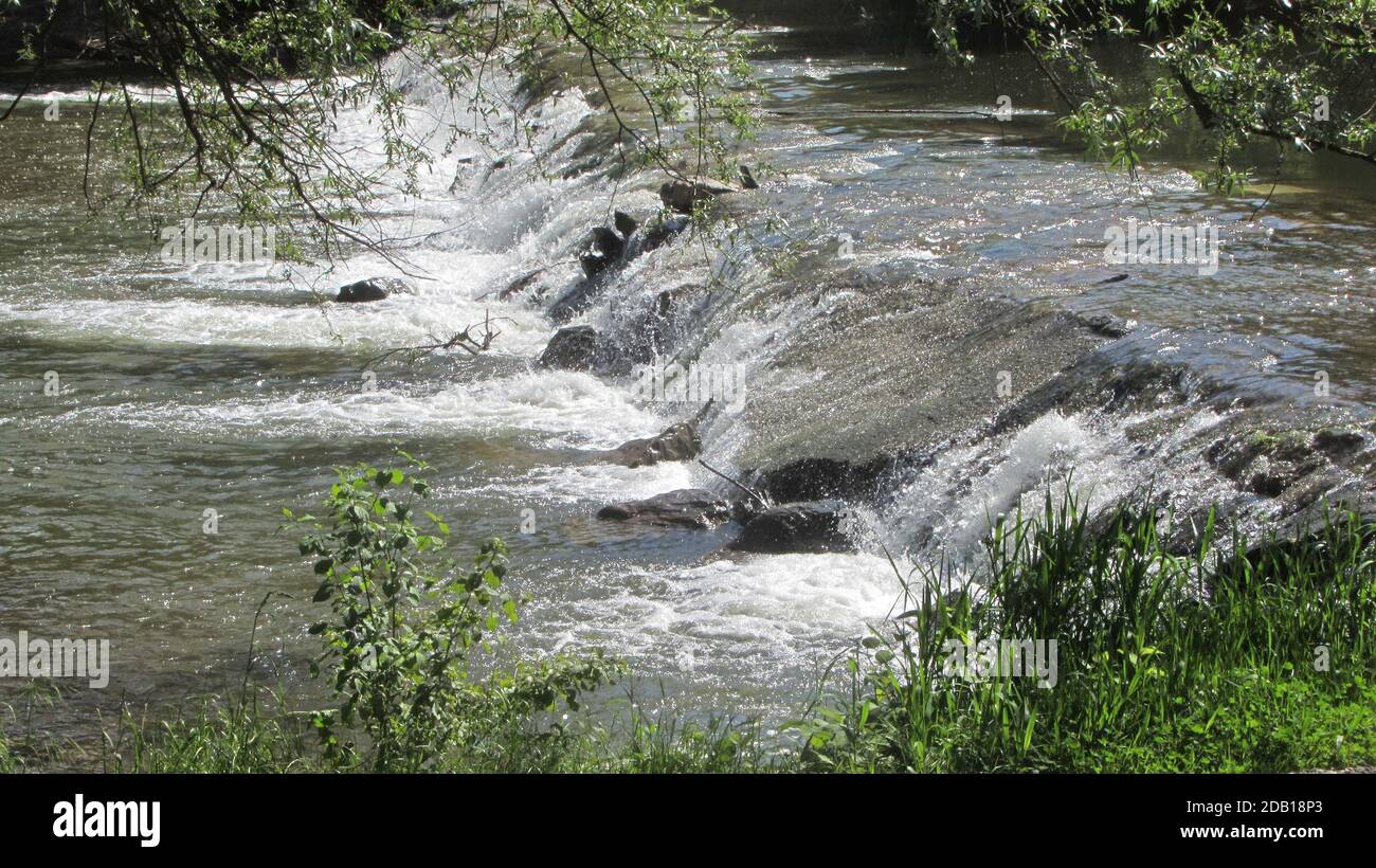 river landscape with a small waterfall and trees at the riverbank Stock ...