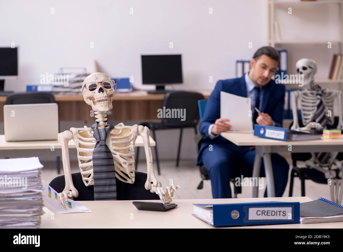 Young employee with skeletons in the office Stock Photo - Alamy