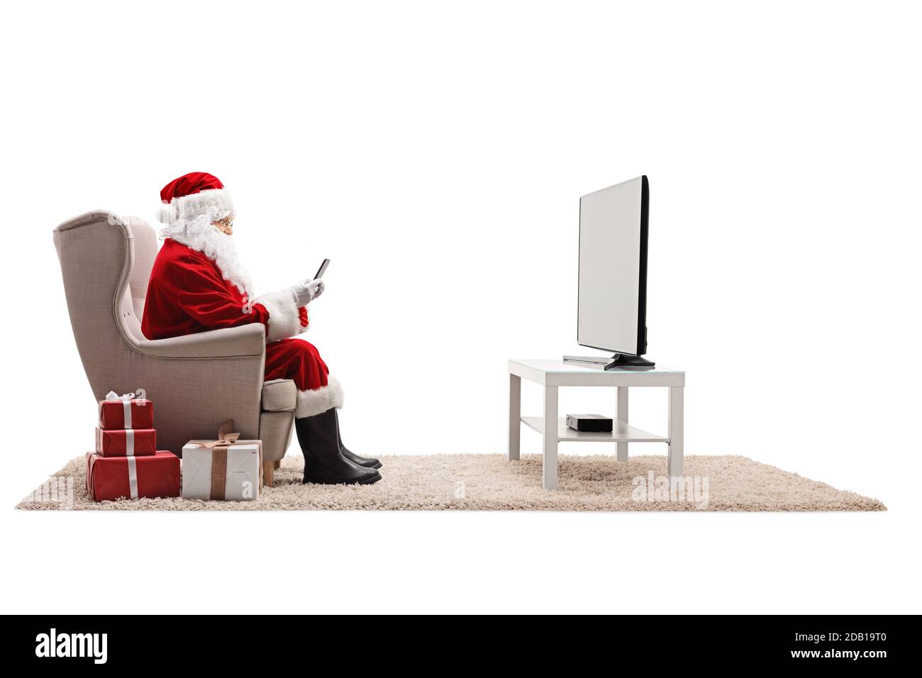 Santa claus using a mobile phone and sitting in an armchair isolated on ...