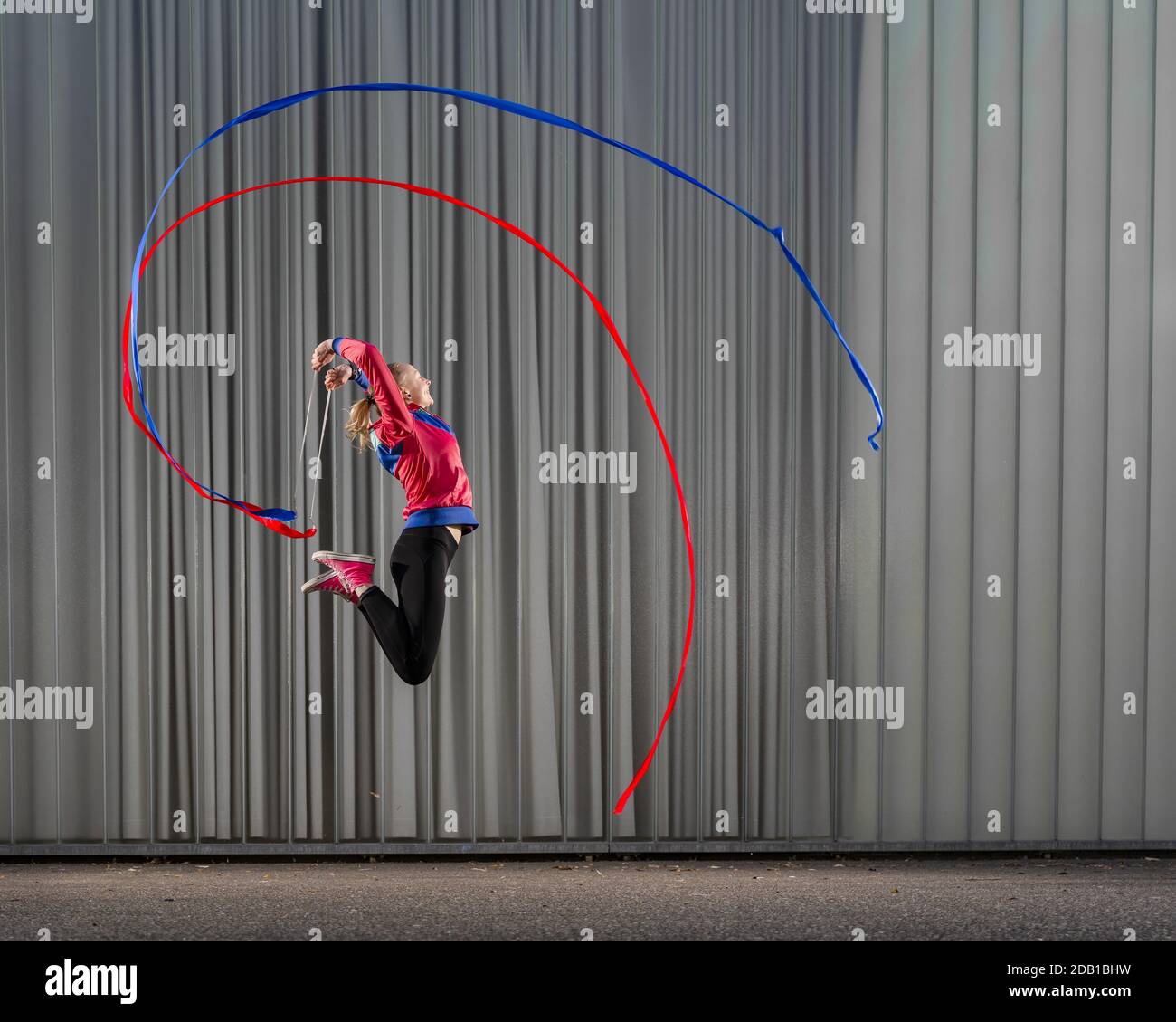 young women in a acrobatic jump in front of a building wall Stock Photo ...