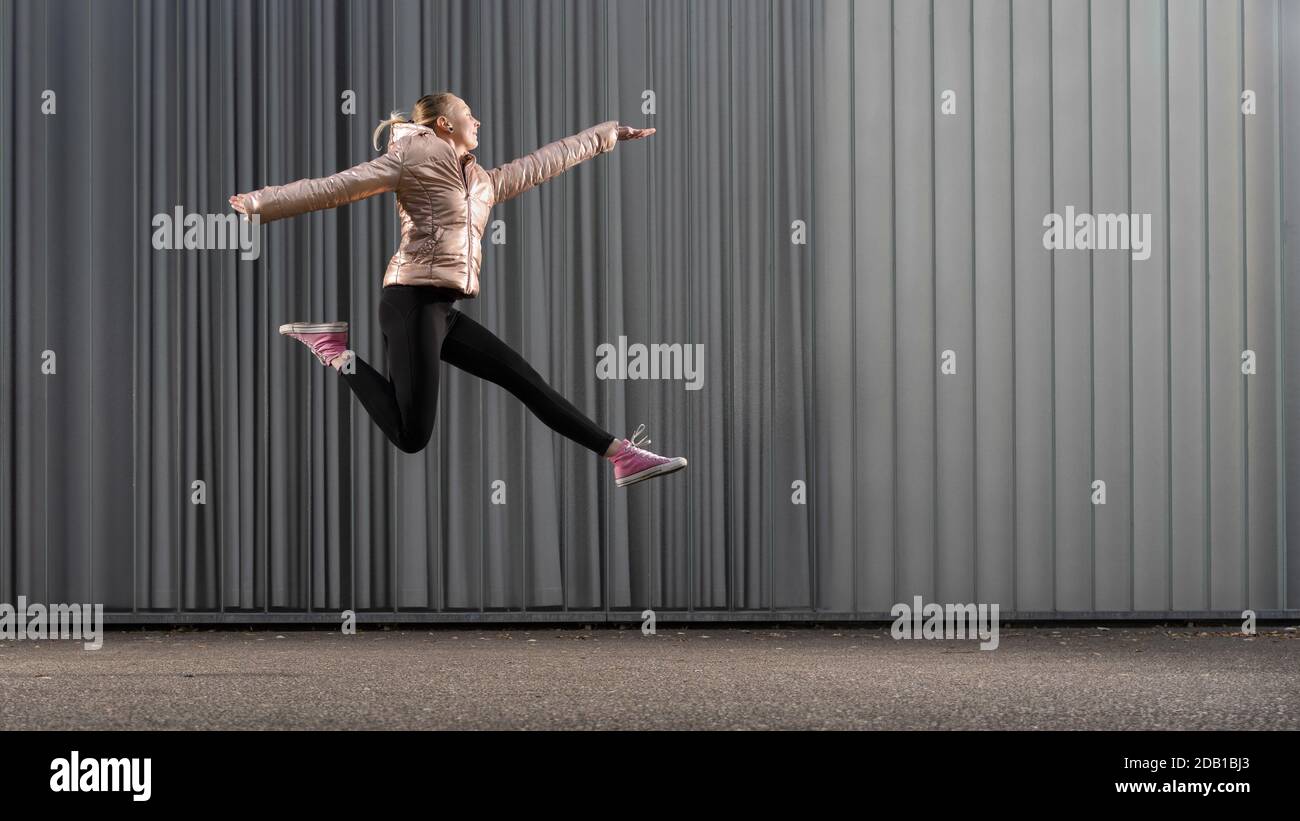 young women in a acrobatic jump in front of a building wall Stock Photo ...