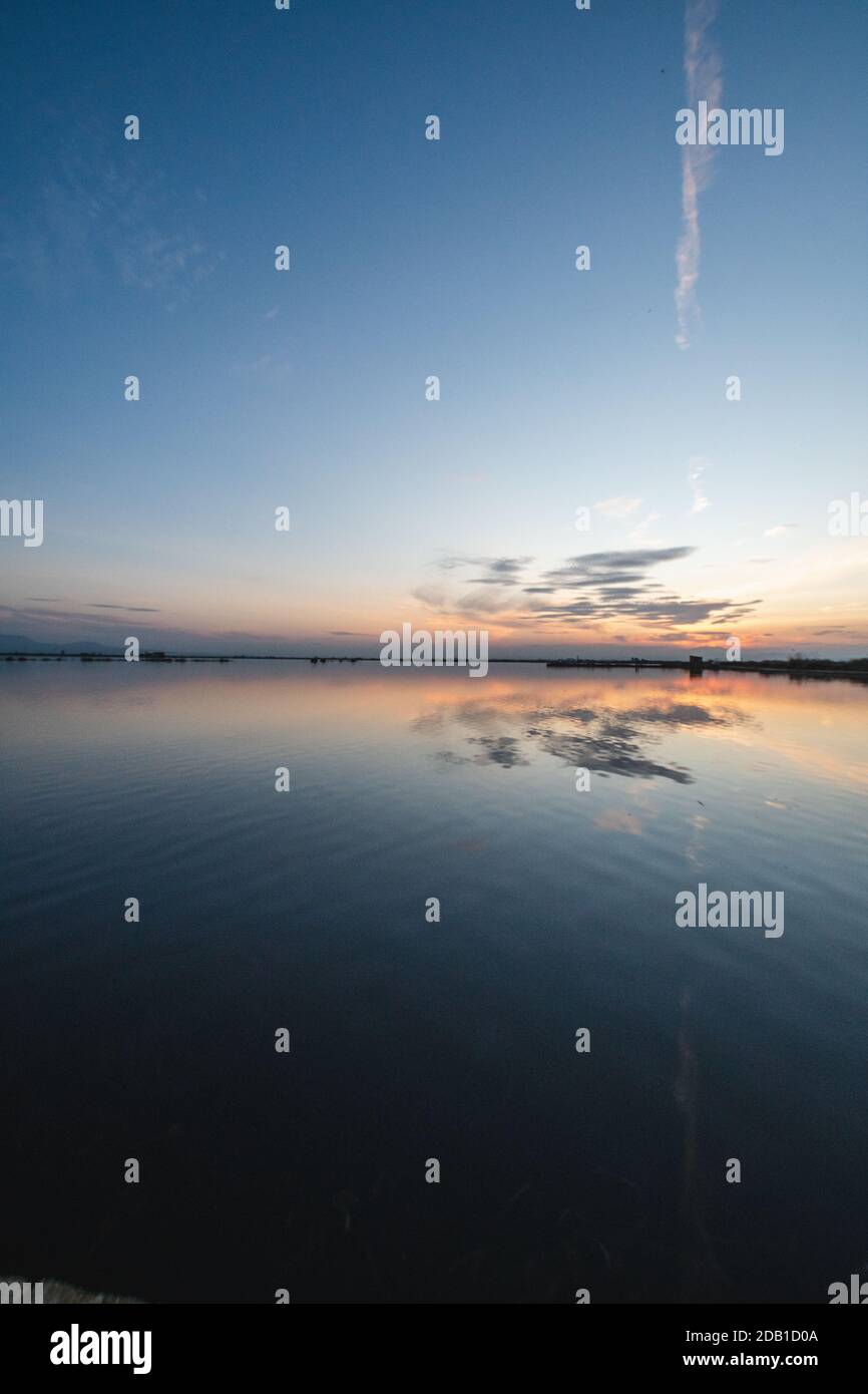 Sunset at albufera lake, with sky reflection and plane Stock Photo - Alamy