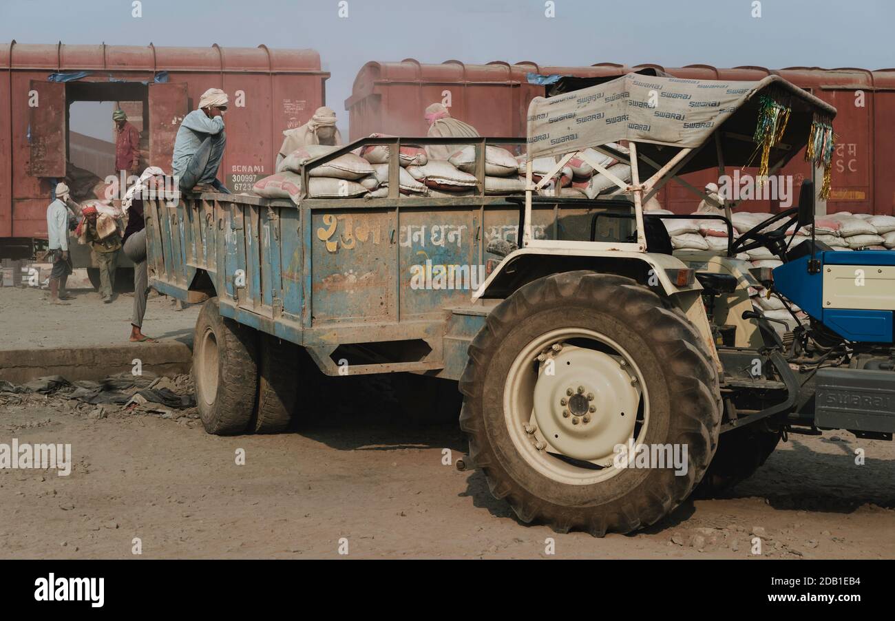 Team of male laborers work in dusty conditions to move heavy bags of ...