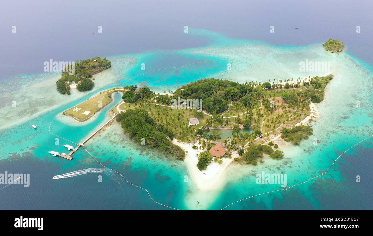 Island with a sandy beach and azure water surrounded by a coral reef ...