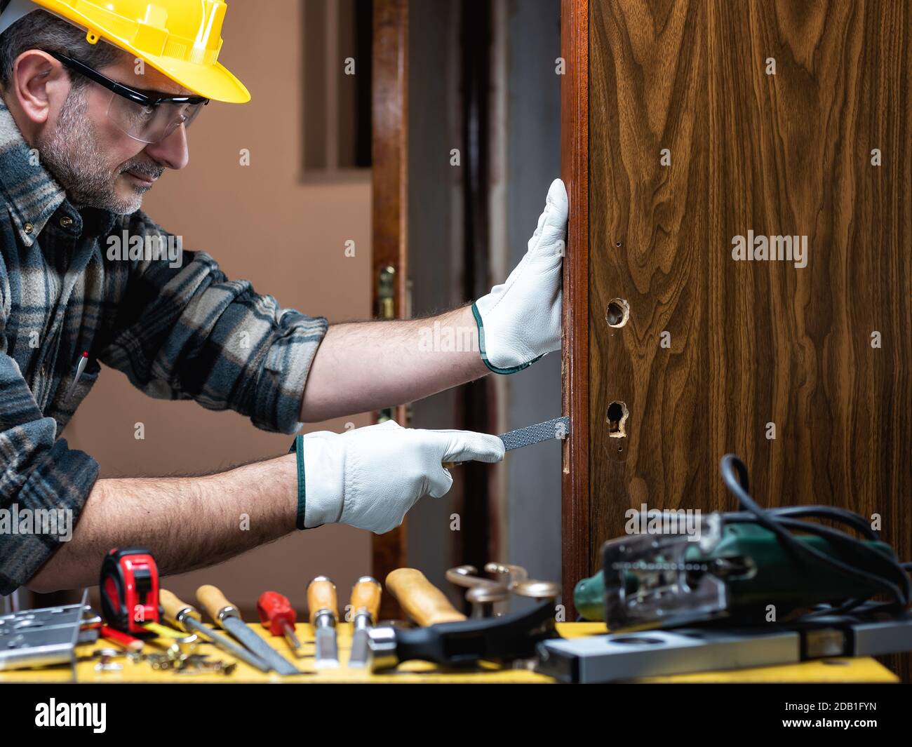 Close-up. Carpenter at work repairs and installs the new lock of a ...